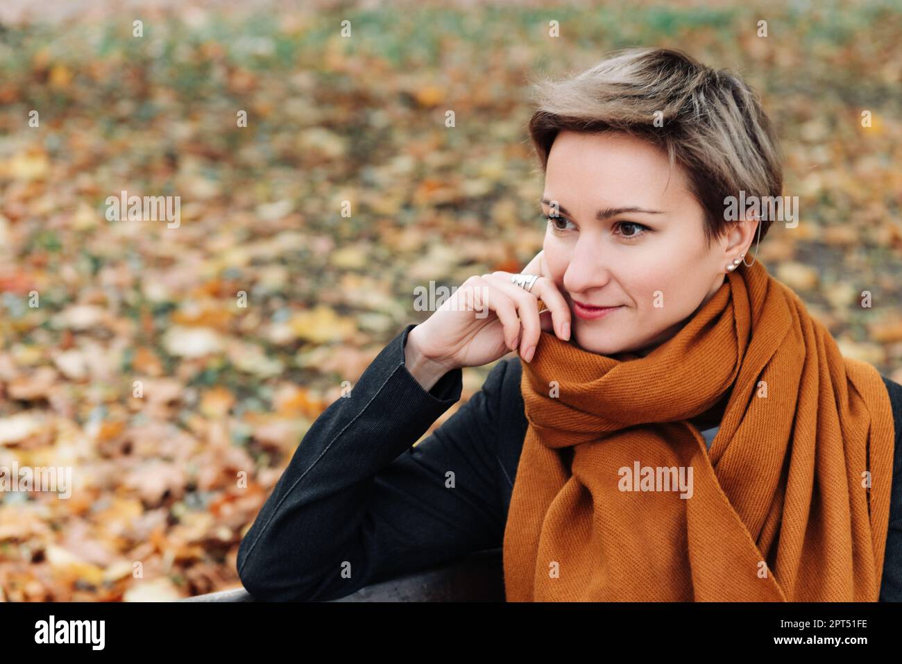 A brooding short-haired woman in autumn in a terracotta scarf Stock ...