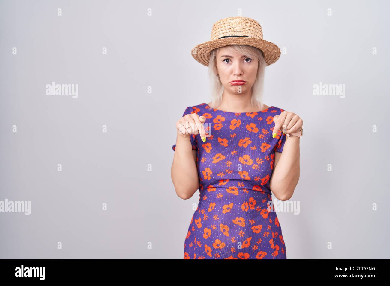 Young caucasian woman wearing flowers dress and summer hat pointing ...