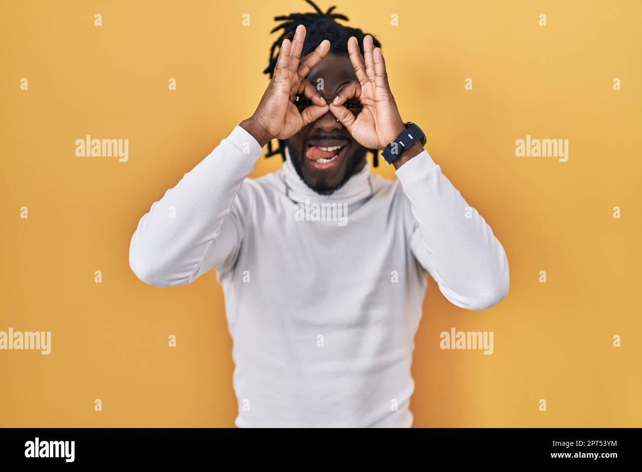 African man with dreadlocks wearing turtleneck sweater over yellow ...