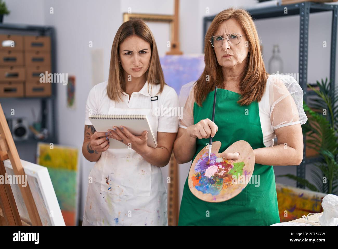 Hispanic mother and daughter painting at paint studio skeptic and ...
