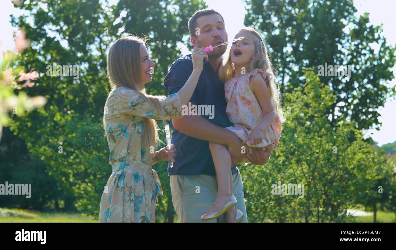 Joyful family spending summer day together outdoor playing with soap ...