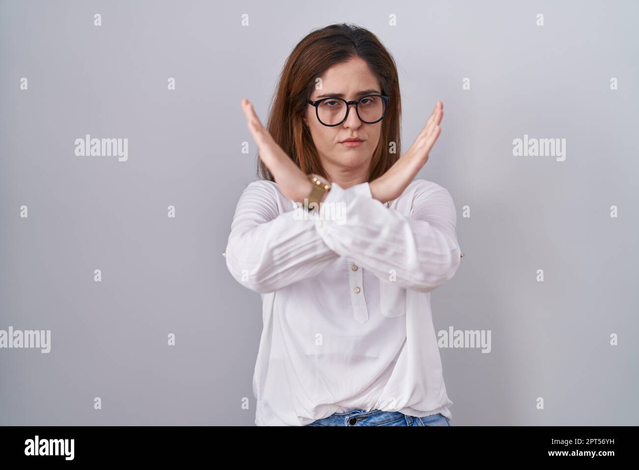 Brunette woman standing over white isolated background rejection ...