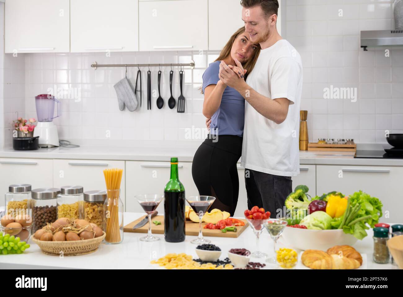 Happy couple in love dancing together in kitchen while preparing and ...