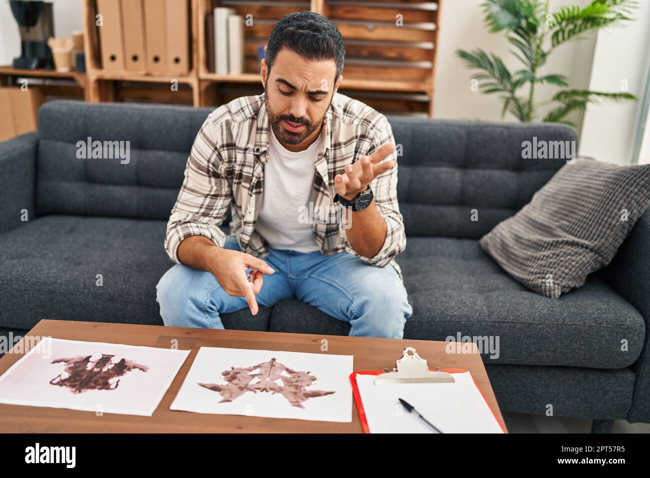 Young hispanic man patient having rorschach test at psychology center ...