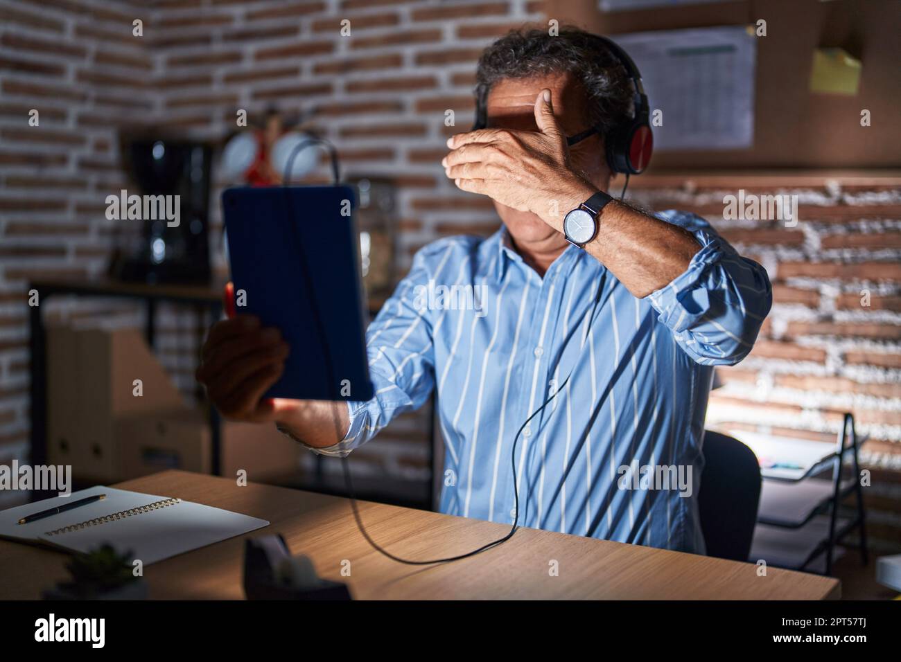 Middle age hispanic man using touchpad sitting on the table at night ...
