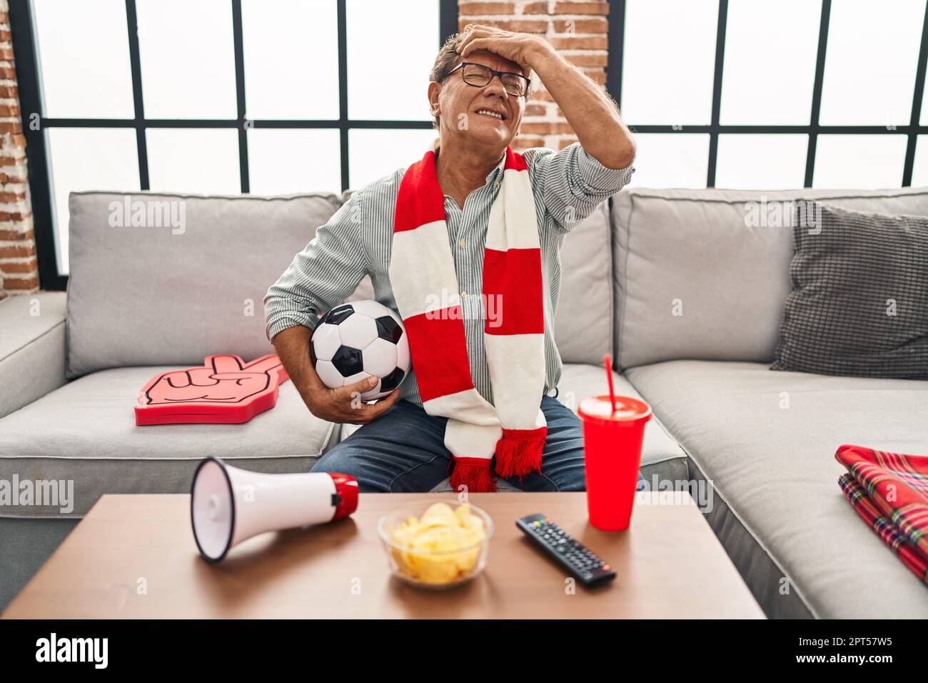 Senior man watching football holding ball supporting team stressed and ...