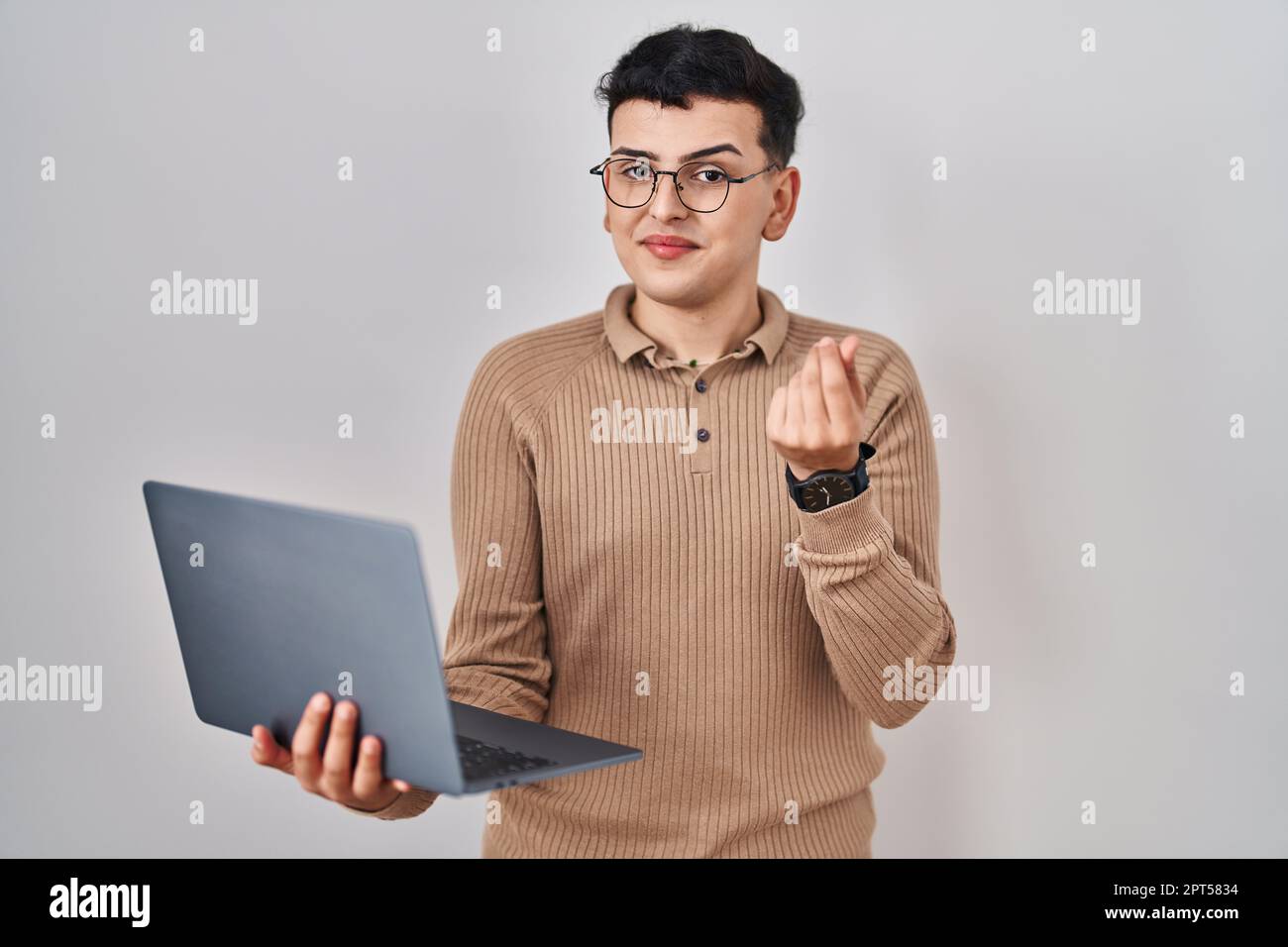 Non binary person using computer laptop doing money gesture with hands ...