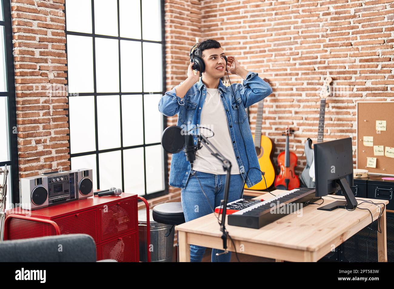 Young non binary man artist listening to music at music studio Stock ...