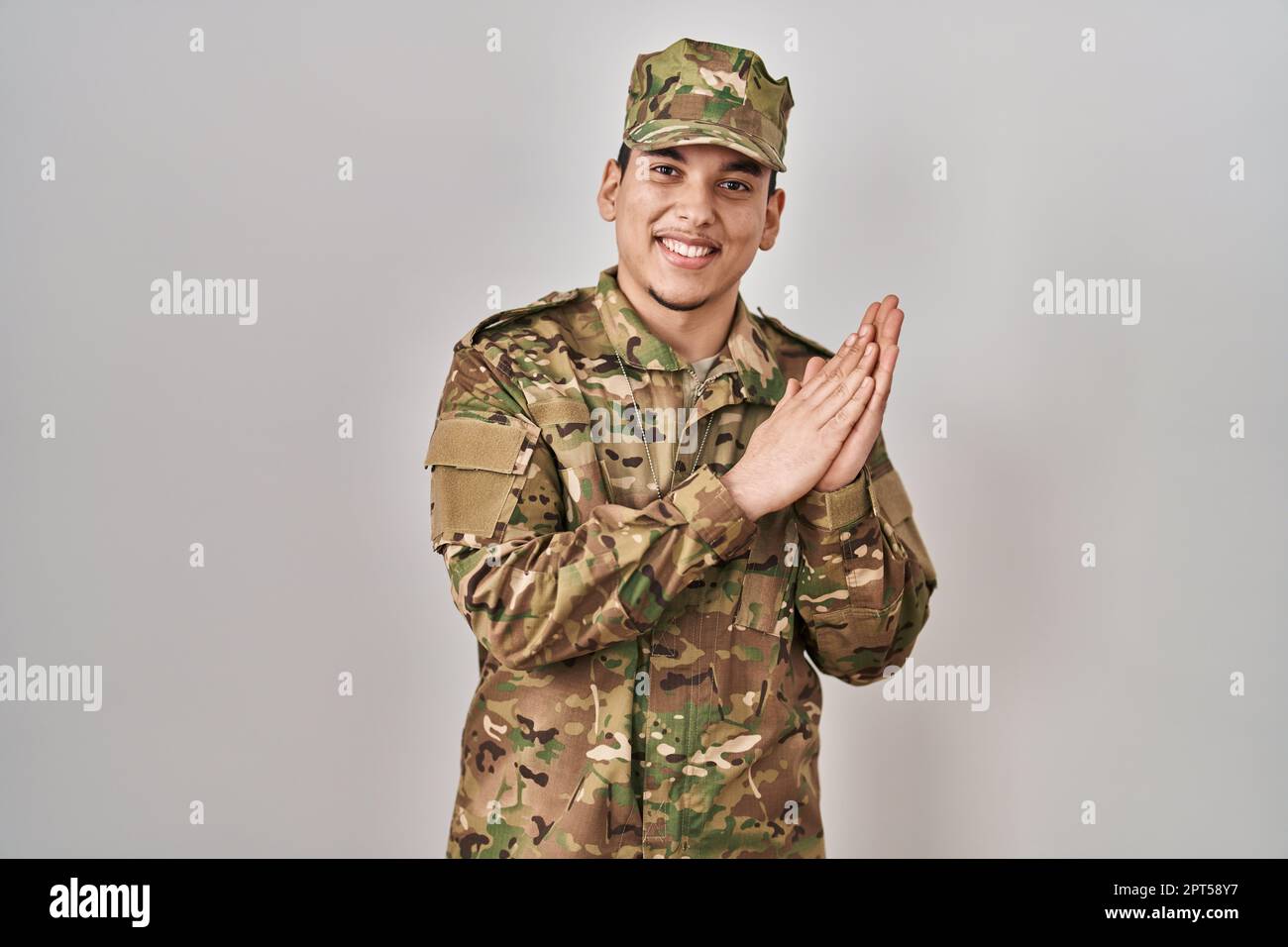 Young arab man wearing camouflage army uniform clapping and applauding ...