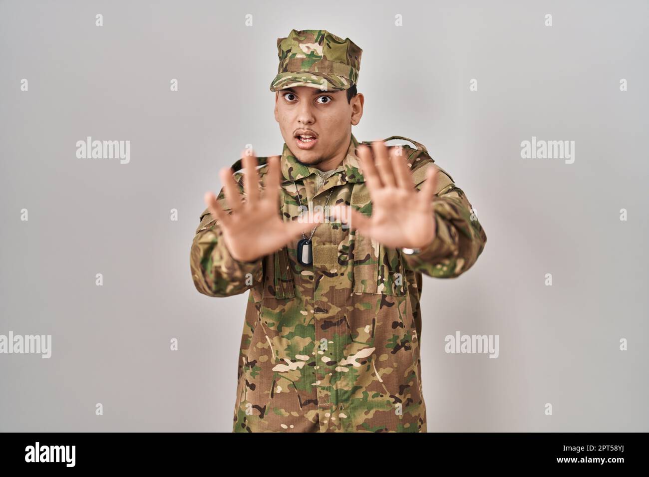 Young arab man wearing camouflage army uniform afraid and terrified ...