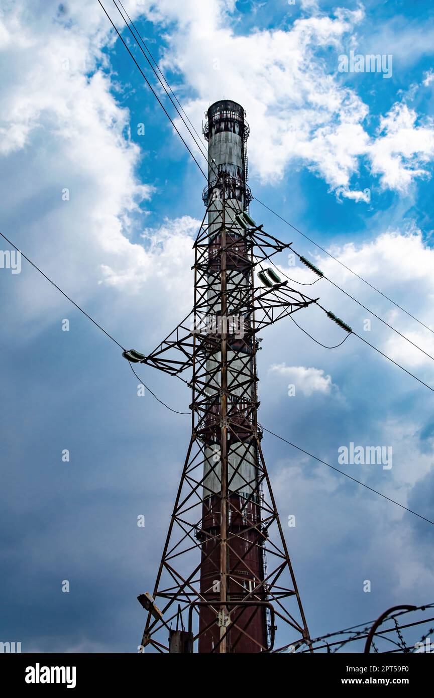 High voltage tower with wires and industrial chimney. High-voltage ...