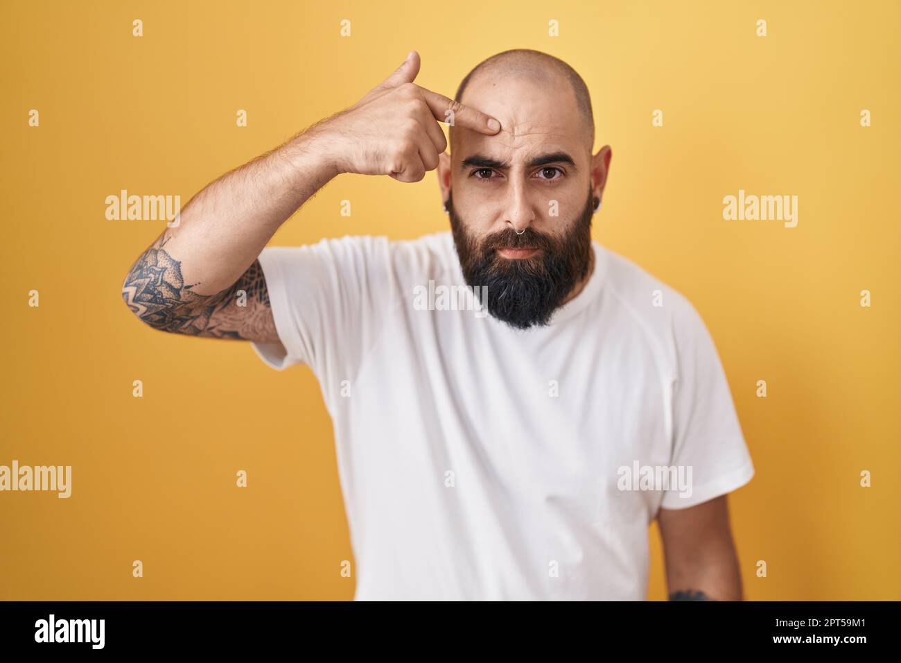 Young hispanic man with beard and tattoos standing over yellow ...
