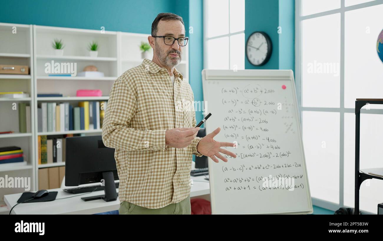 Middle age man teacher teaching maths lesson at classroom Stock Photo ...