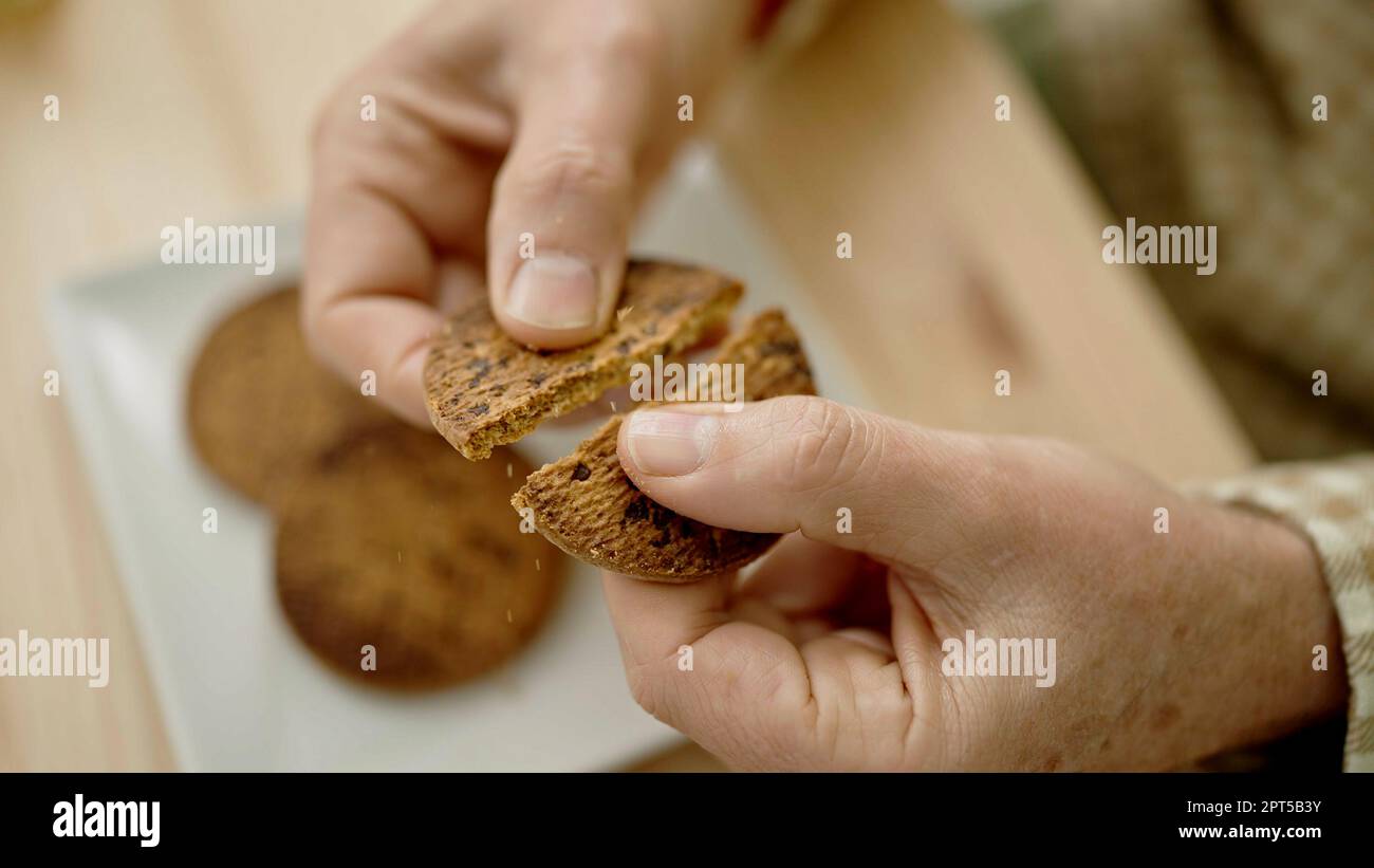 Middle age man breaking cookie at home Stock Photo - Alamy