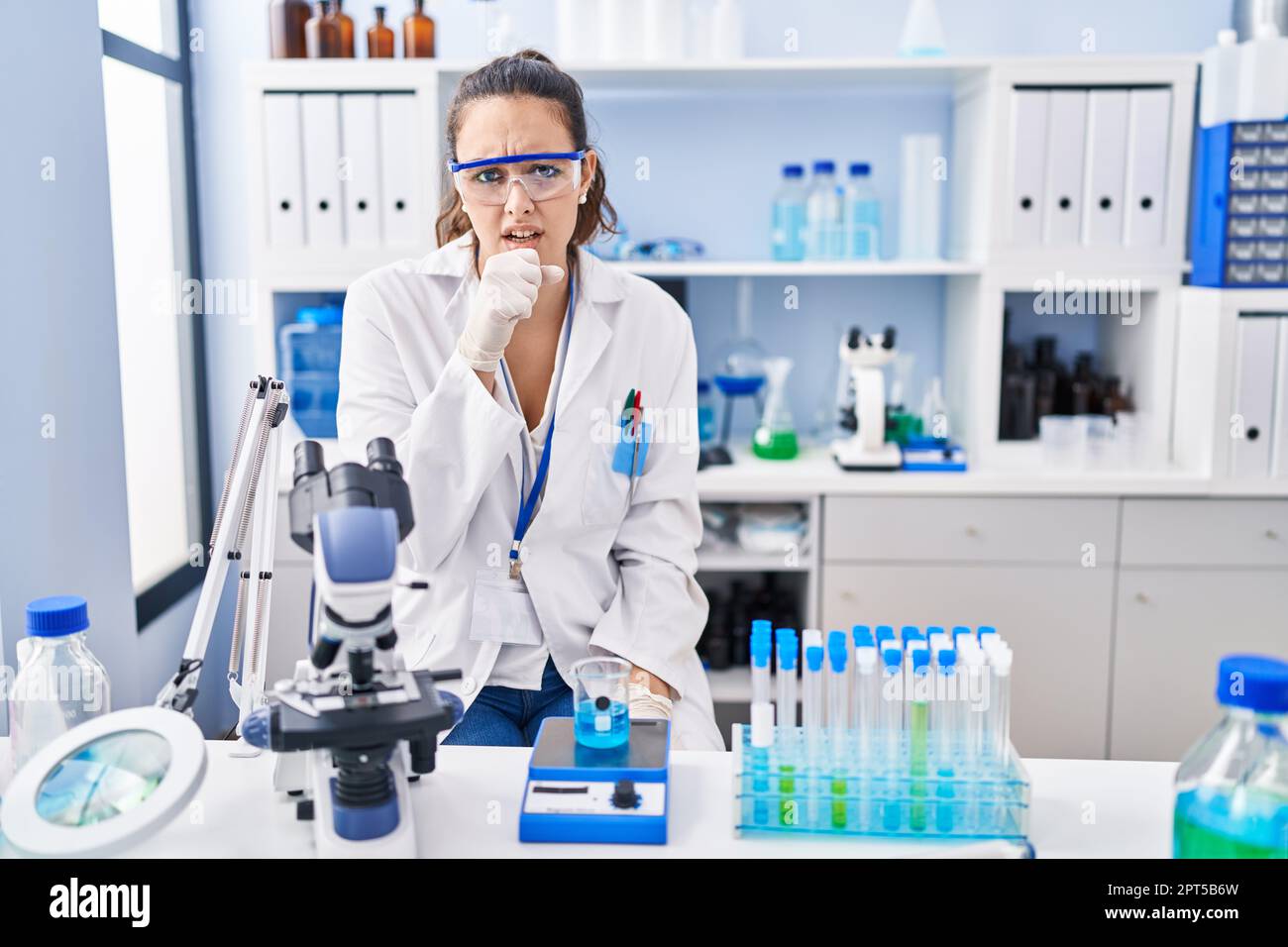 Young hispanic woman working at scientist laboratory feeling unwell and ...