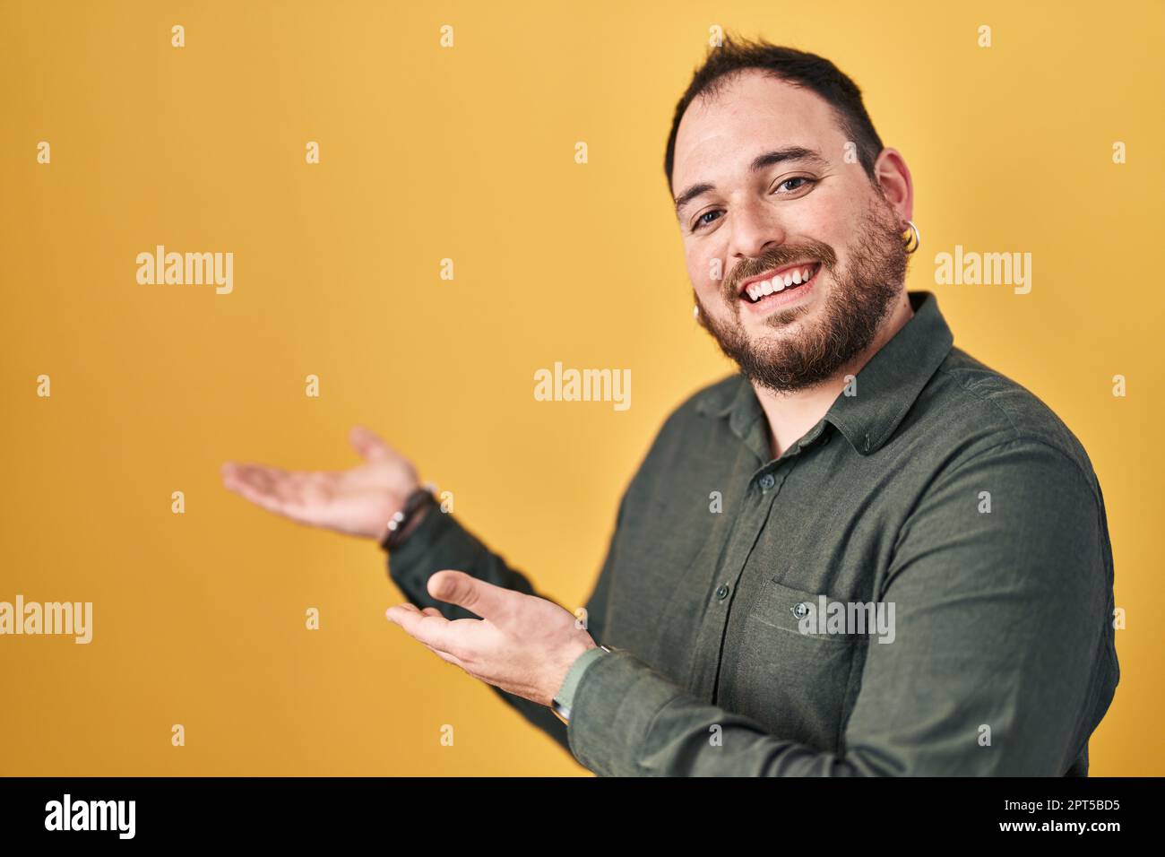 Plus size hispanic man with beard standing over yellow background ...