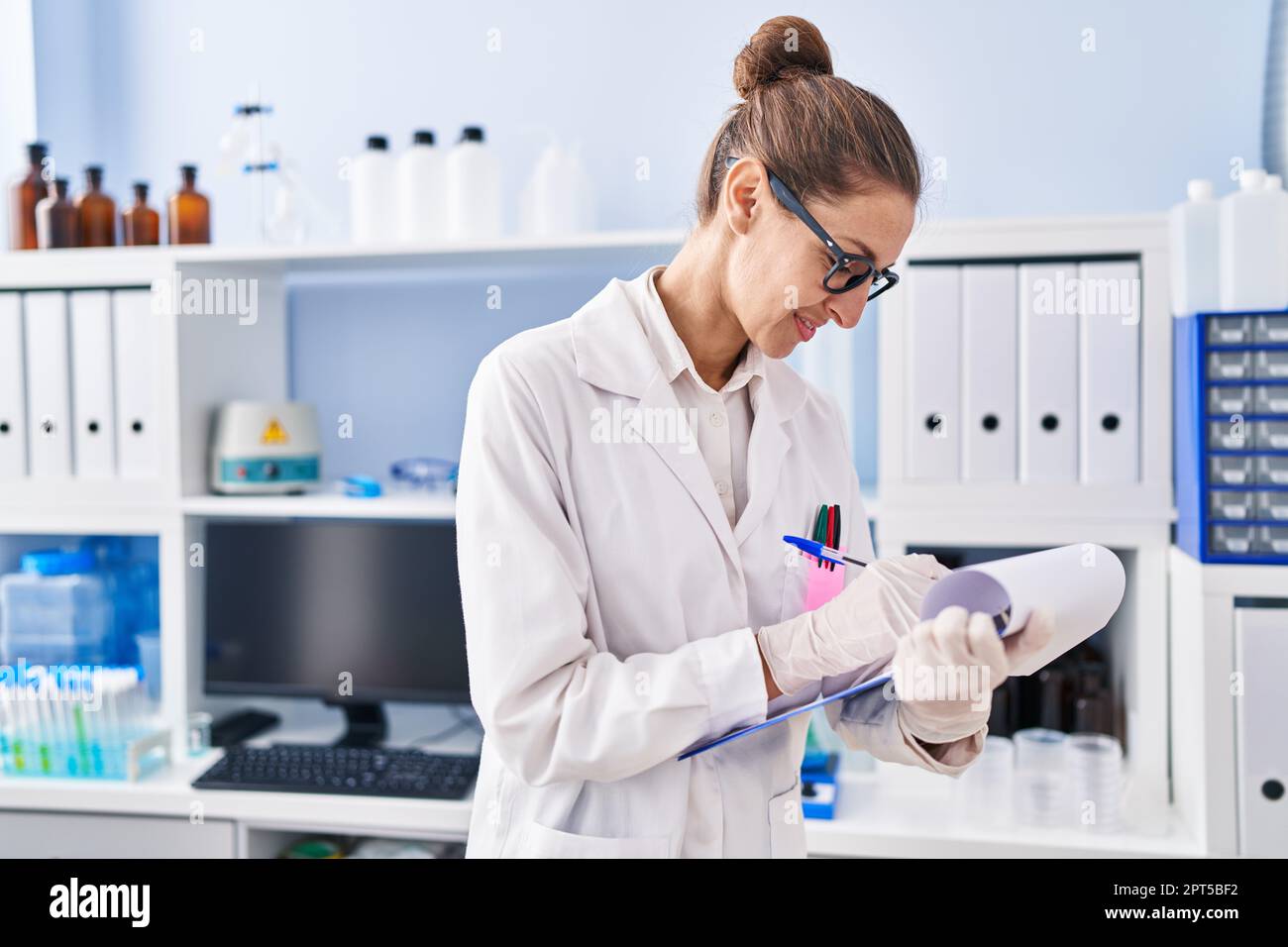 Young woman scientist writing on clipboard at laboratory Stock Photo ...