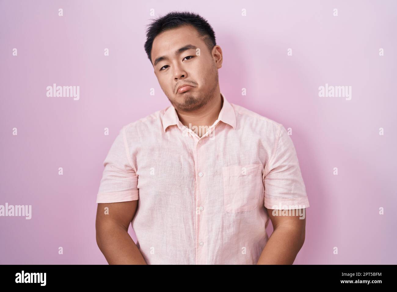 Chinese young man standing over pink background depressed and worry for ...