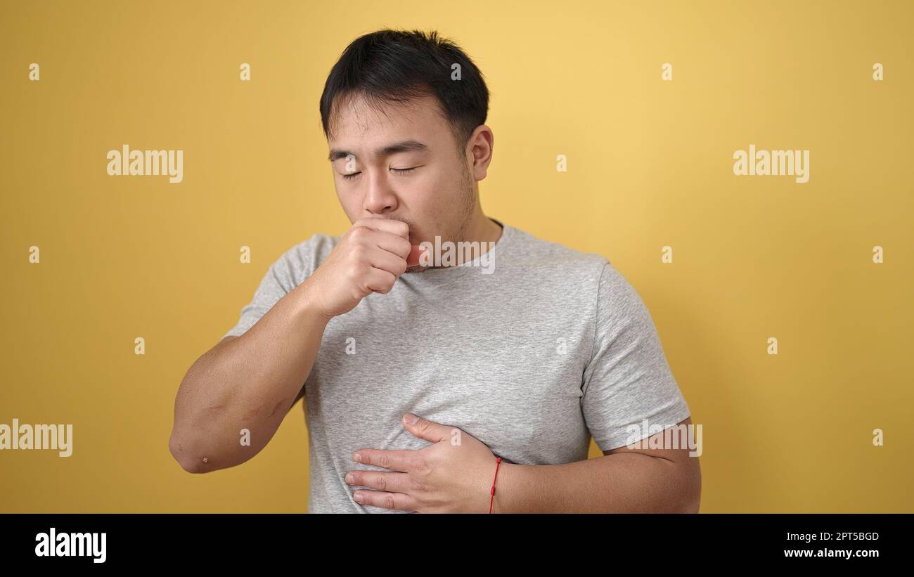 Young chinese man coughing over isolated yellow background Stock Photo ...