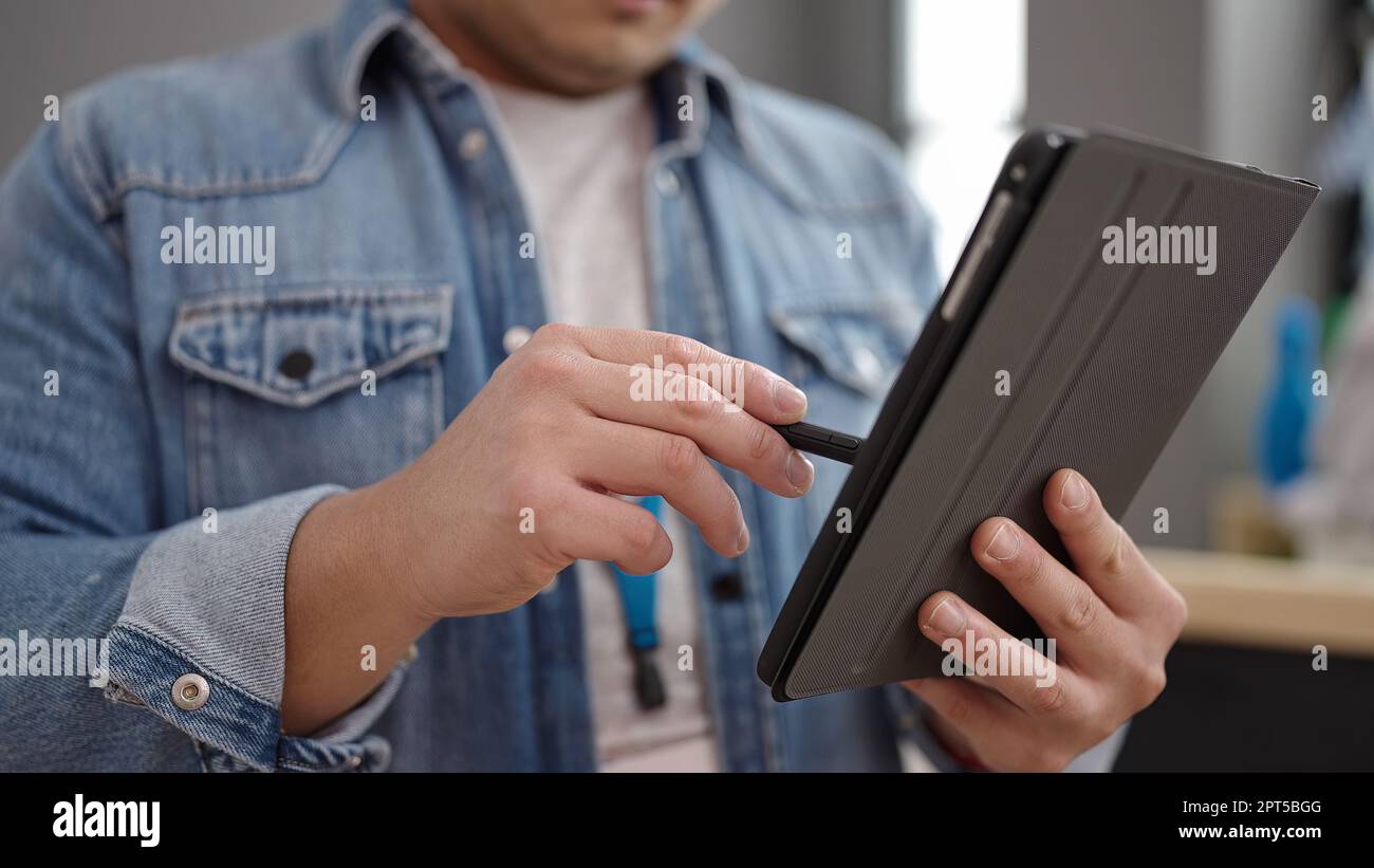 Young chinese man preschool teacher using touchpad standing at ...