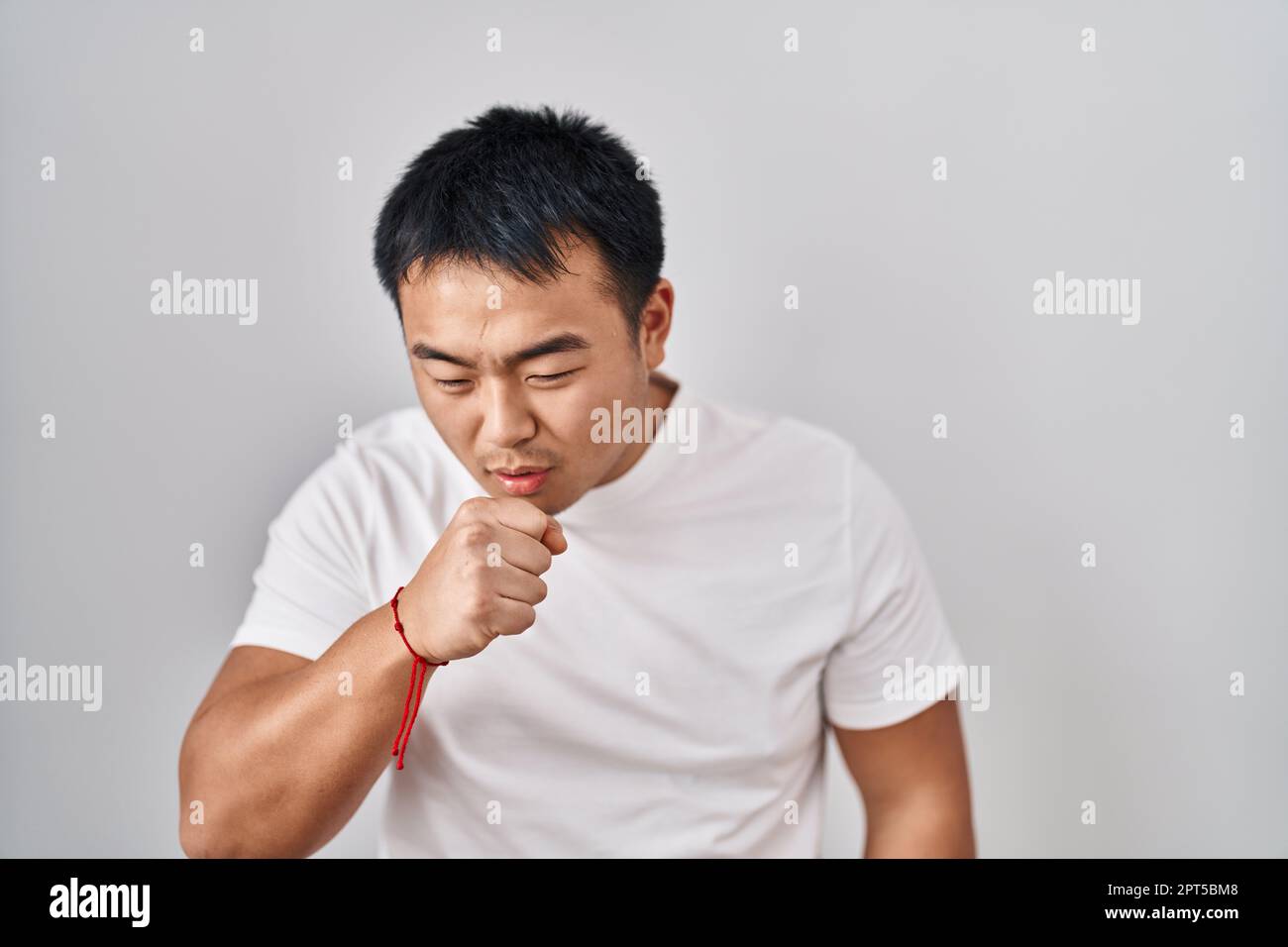 Young chinese man standing over white background feeling unwell and ...