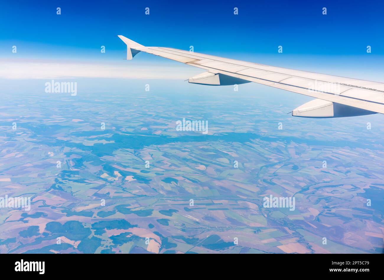 Aerial view from airplane window above green ground. View from the ...