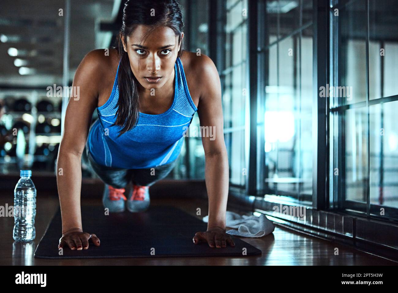 Conditioning her body. an attractive young woman doing pushups as part ...