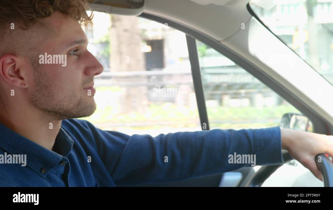 Side view of Caucasian handsome joyful male driver sitting in car with ...