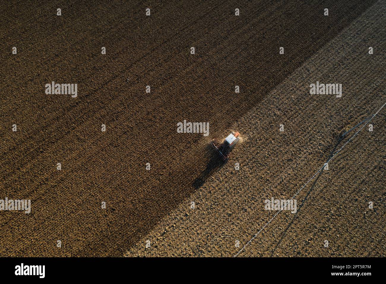 farmer driving a crawler tractor drags a cloud of dust behind ...
