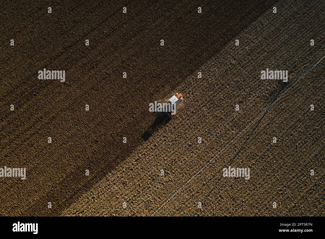 farmer driving a crawler tractor drags a cloud of dust behind ...