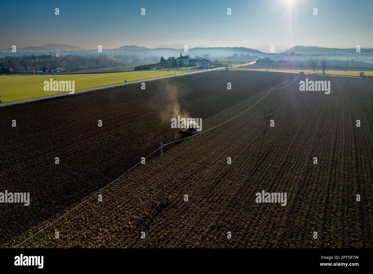 farmer driving a crawler tractor drags a cloud of dust behind ...