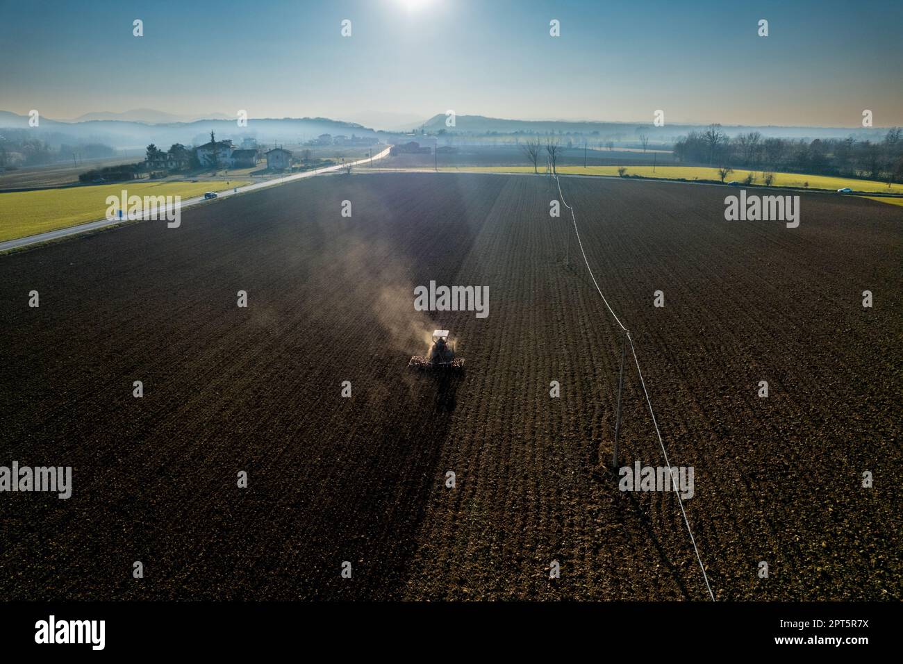 farmer driving a crawler tractor drags a cloud of dust behind ...