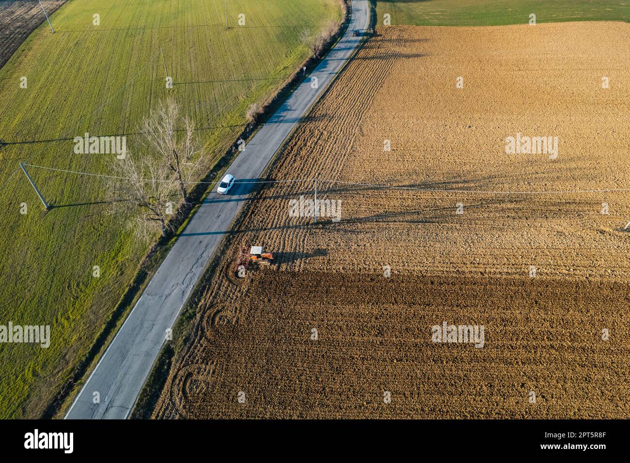 farmer driving a crawler tractor drags a cloud of dust behind ...