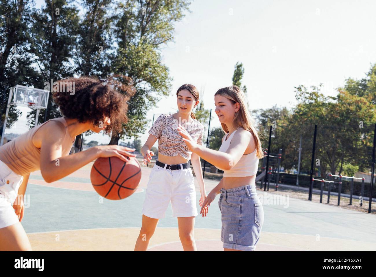 Multicultural group of young female friends bonding outdoors and having ...