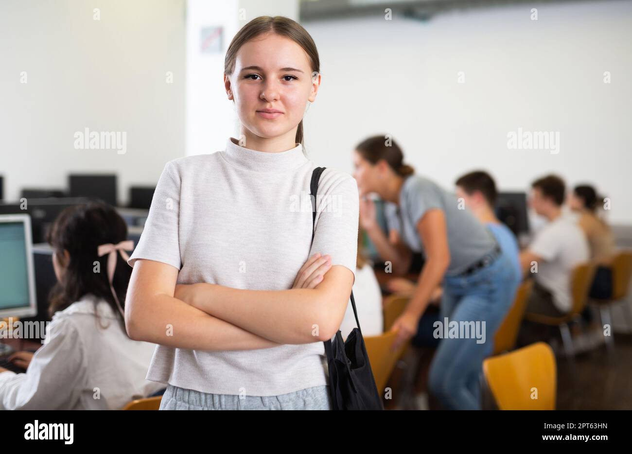 Confident interested female student standing in technology classroom ...