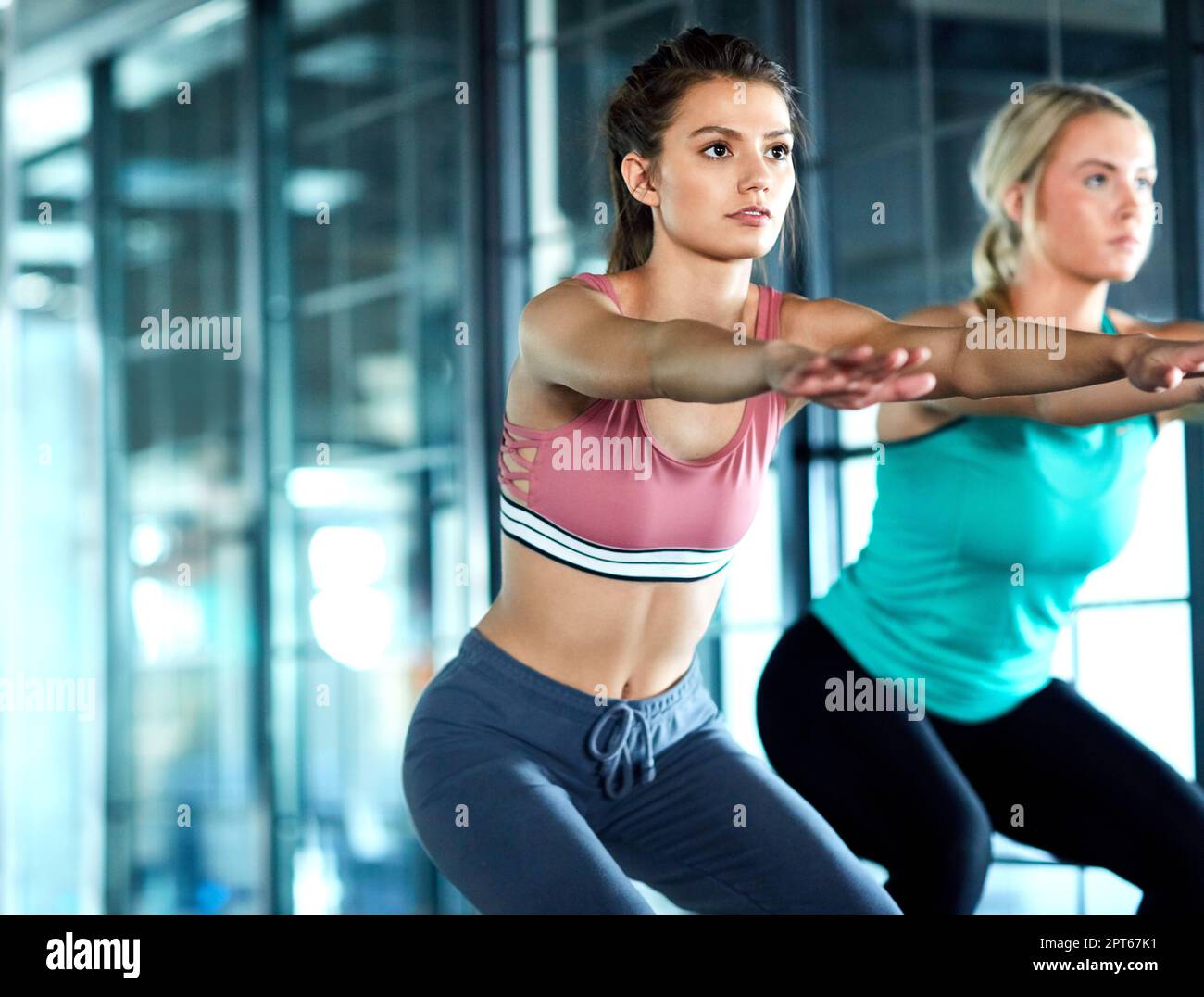 Progressing together. two attractive young women working out together ...