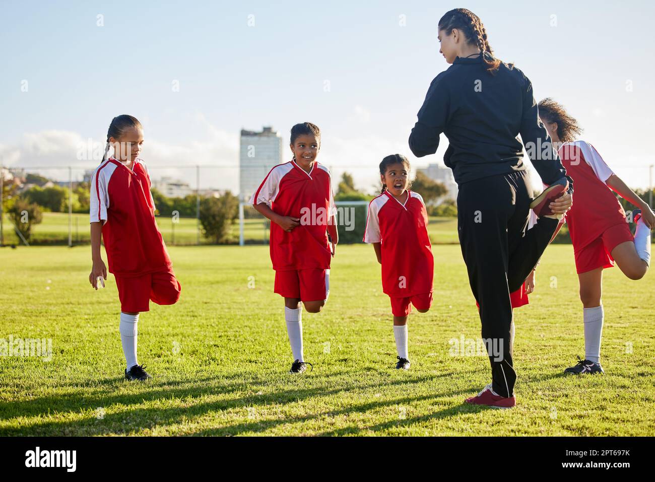 Team, soccer and girls stretching in football stadium with coach in ...