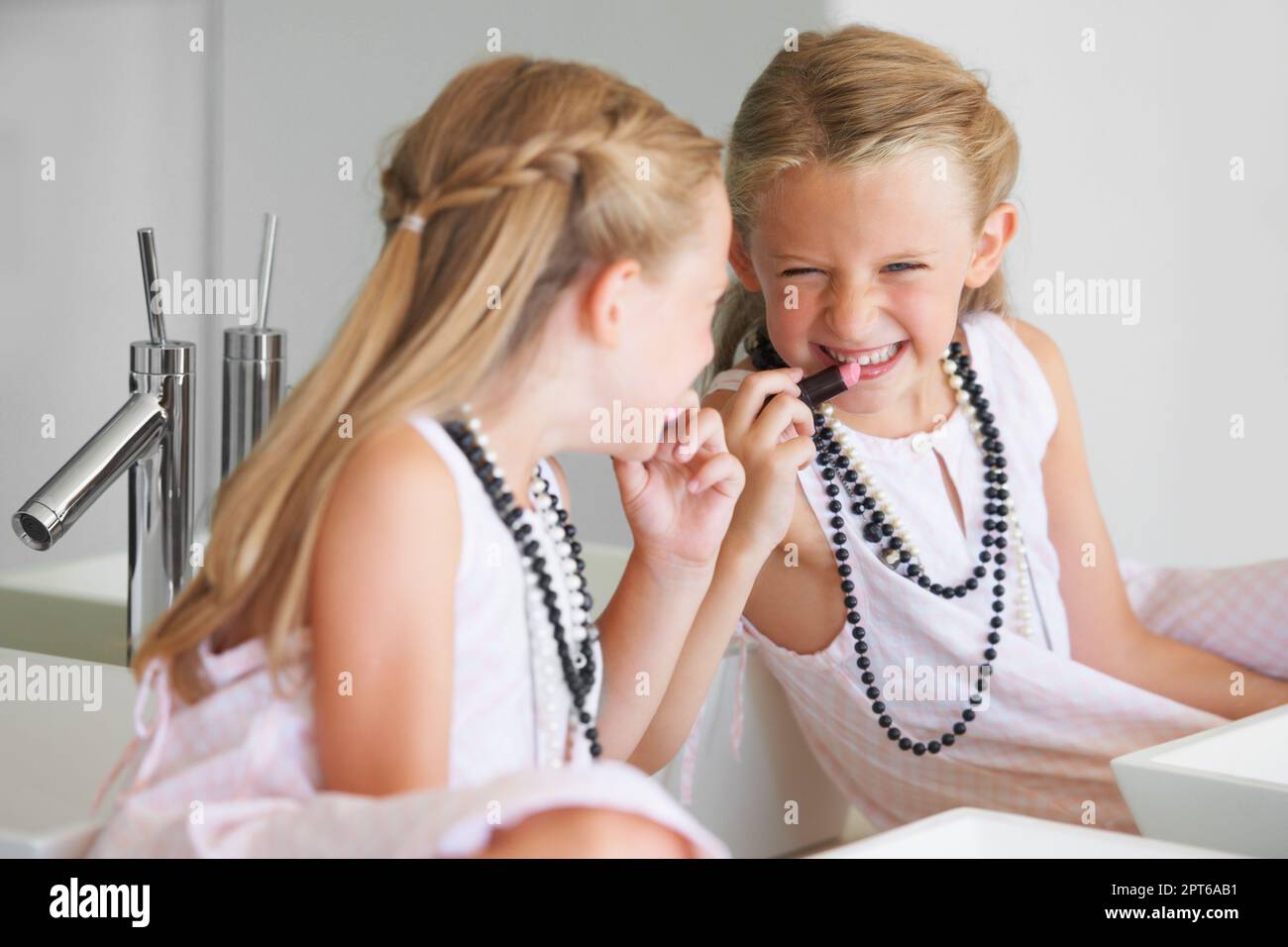 Plotting something mischievious. Naughty little girl in front of a mirror with her mothers ...