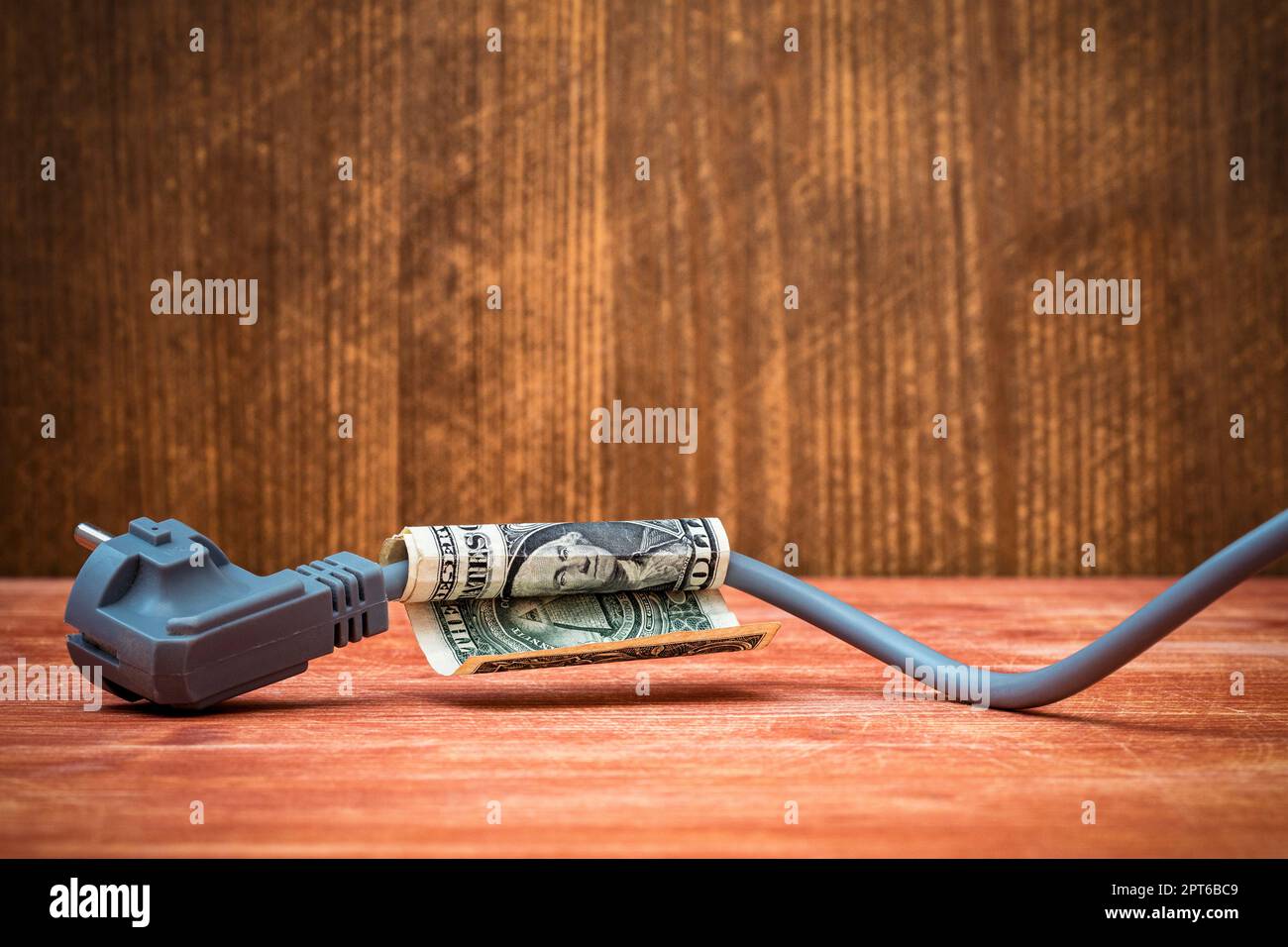 Electric plug and rolled up dollar banknote. The concept of the energy ...