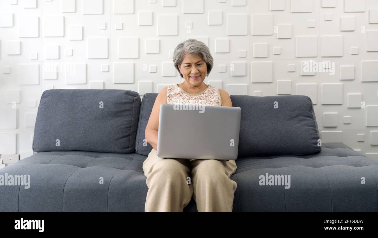 Asian gray hair old woman looking at laptop computer monitor, smiling ...