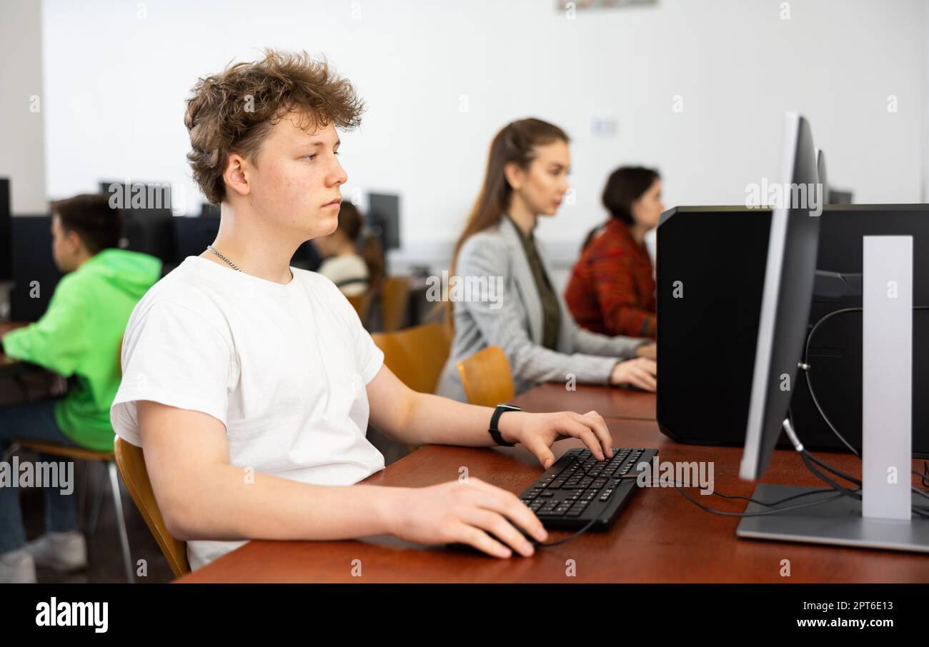 Teenage boy using computer during lesson Stock Photo - Alamy