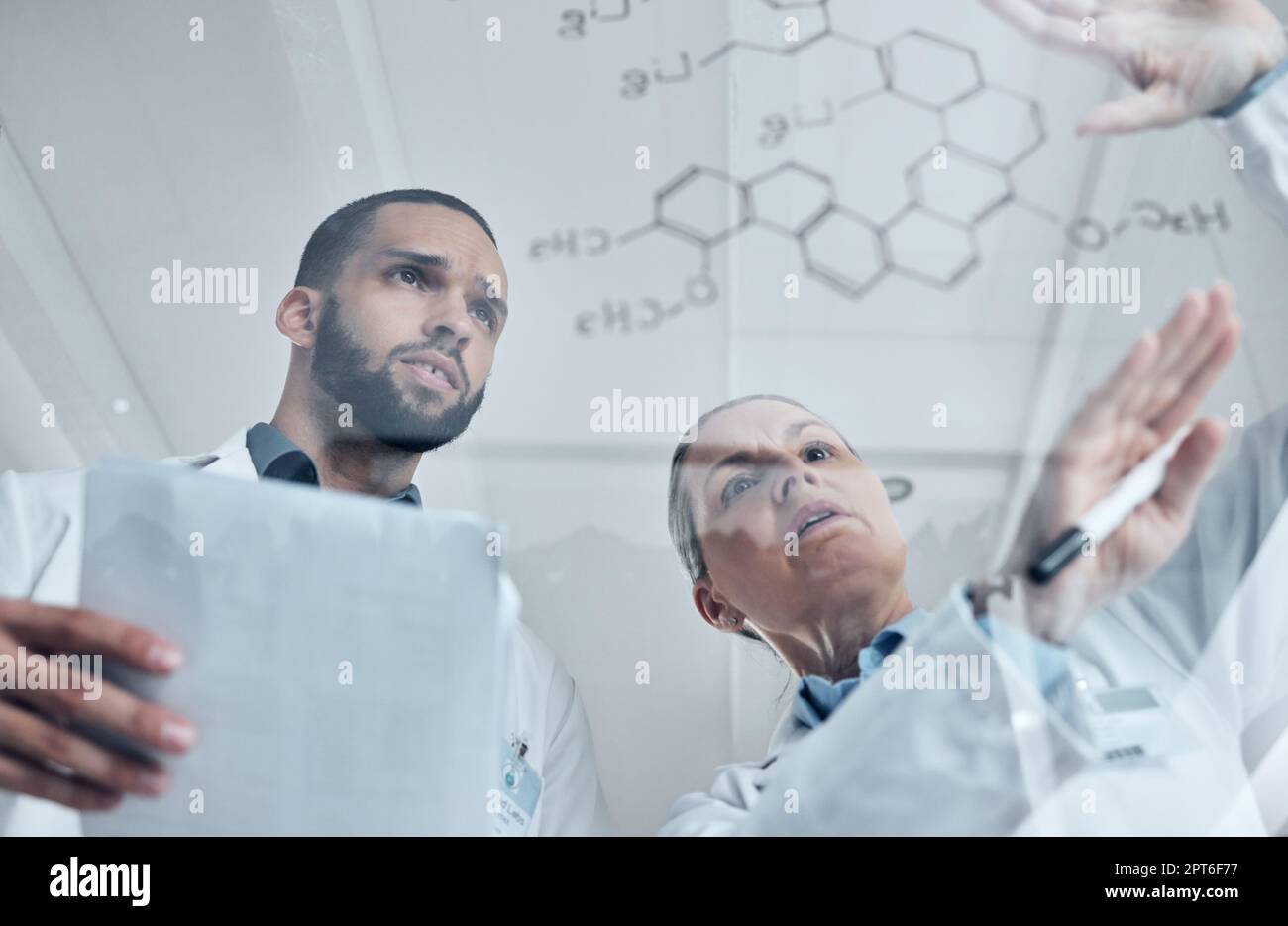 Scientist team, science and chemistry formula on glass board while solving or discuss experiment ...