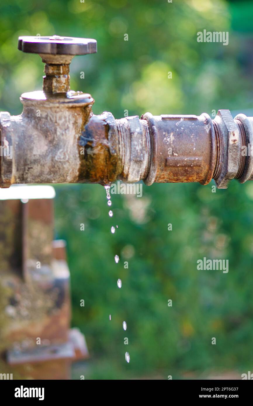Dripping tap of a water tank in the open . Drops fall from the pipe ...