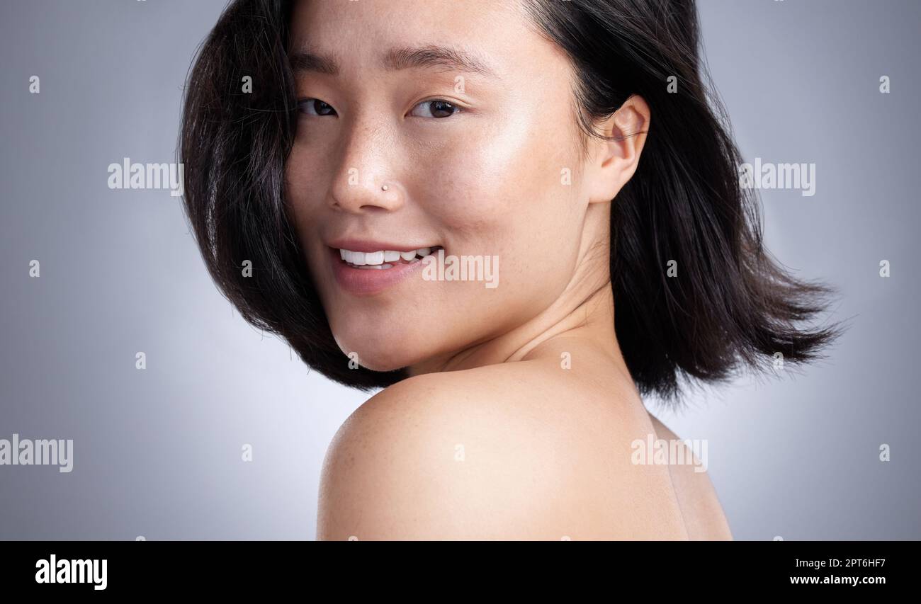 I look good from every angle. a young woman standing against a grey ...