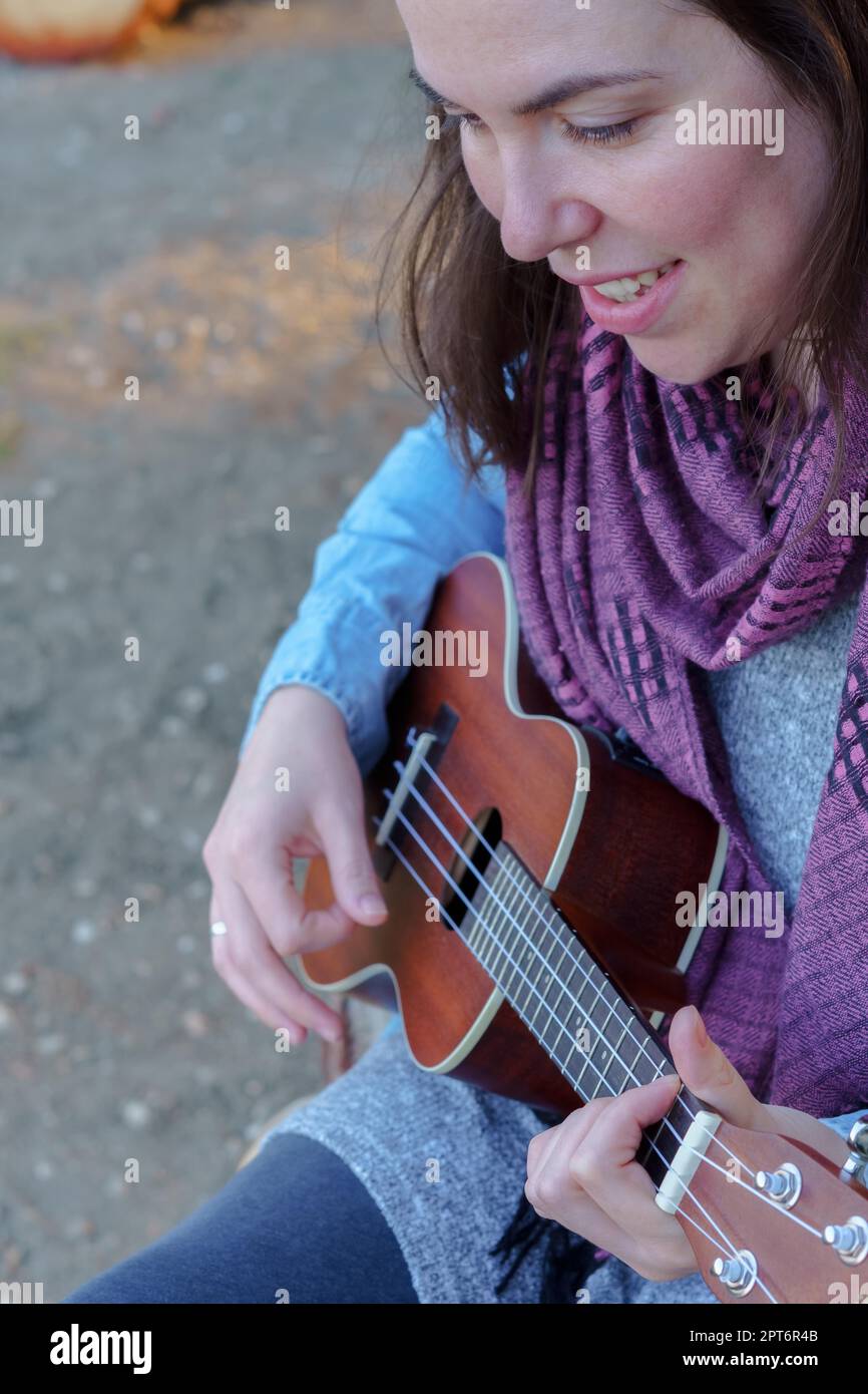Top view of a young brunette girl with long hair playing the ukulele ...