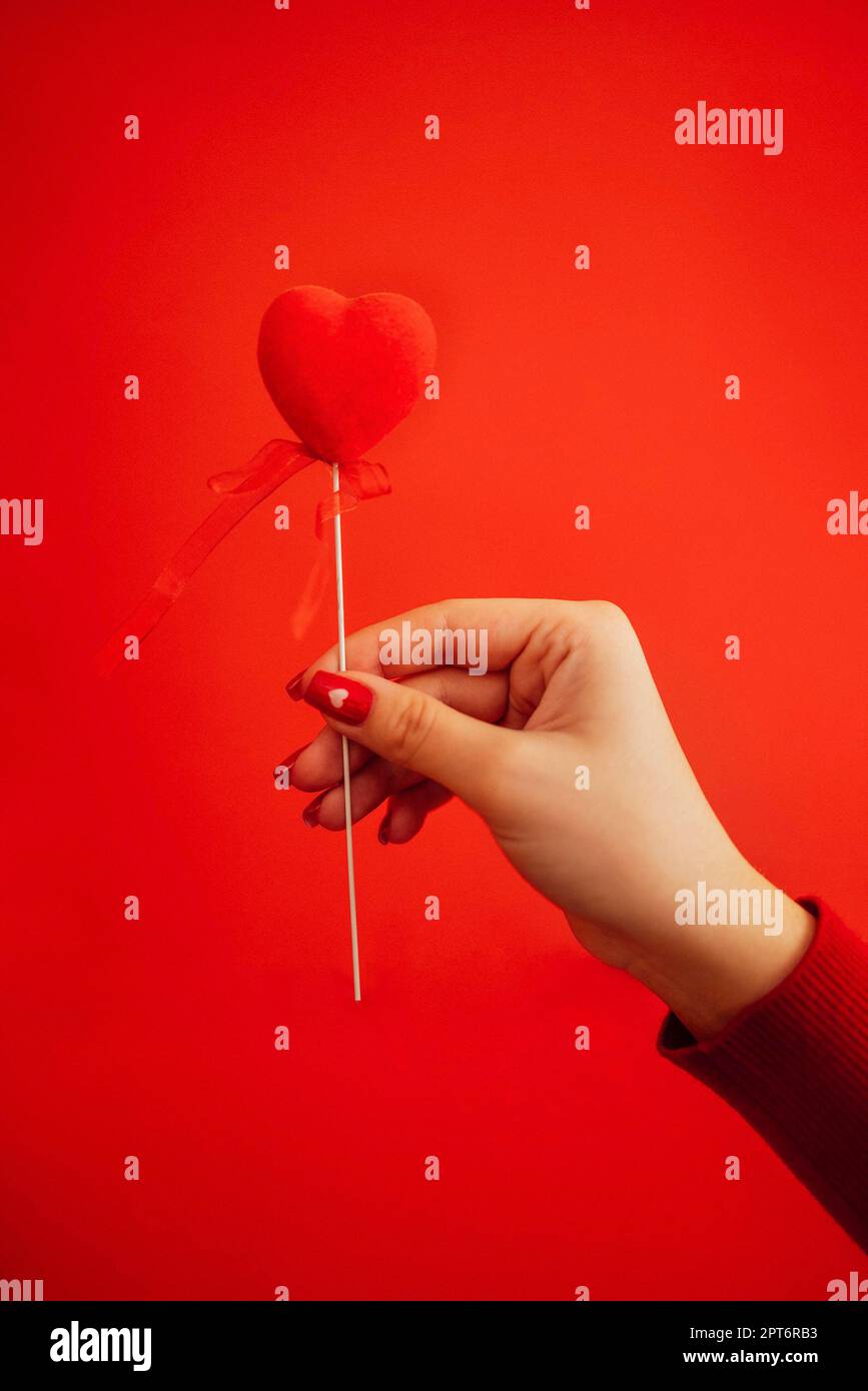 Decorative heart on a stick with ribbon in hand of the woman. Bright ...