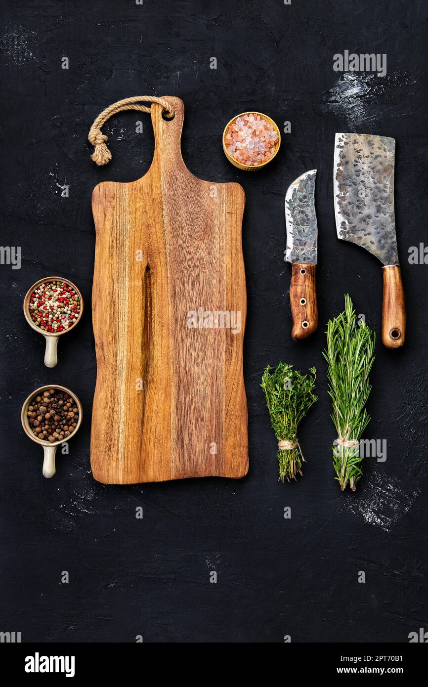Top view of wooden cutting board with butcher tools and herbs with ...