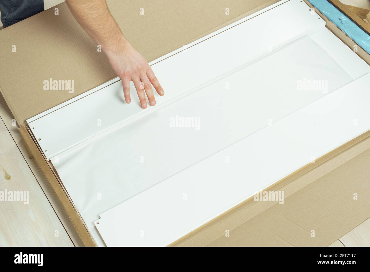 Male hands unpacking cardboard box with parts for assembling white ...