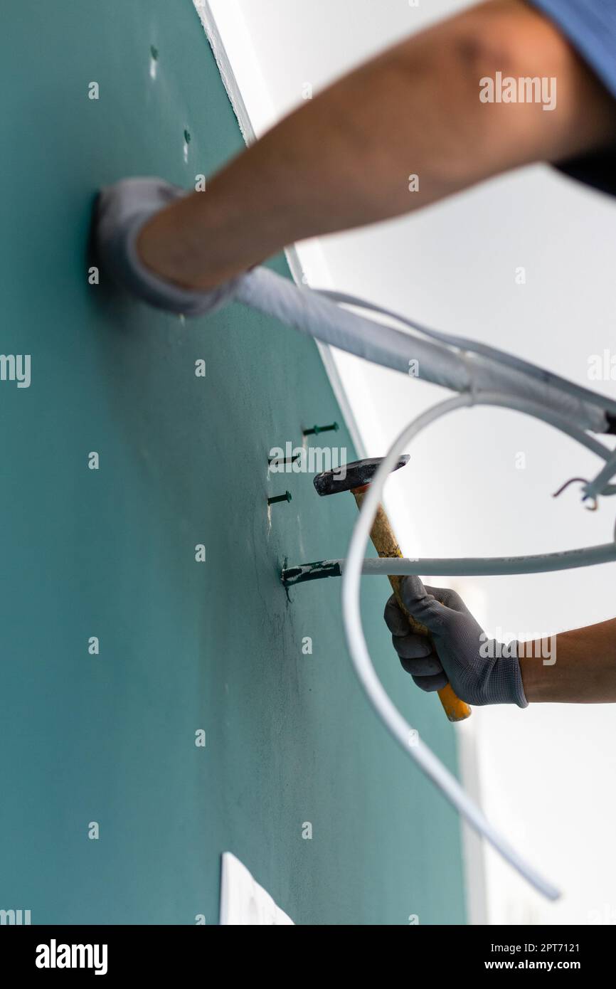 Close up of hammering nail in wall. Male worker drives dowels into wall ...