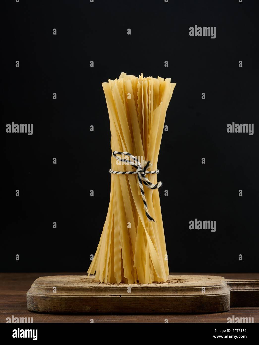 A bunch of fresh noodles tied with a rope on a brown wooden board ...